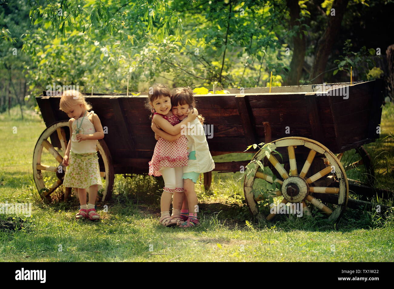 Three girls in the park near the old carts Stock Photo - Alamy