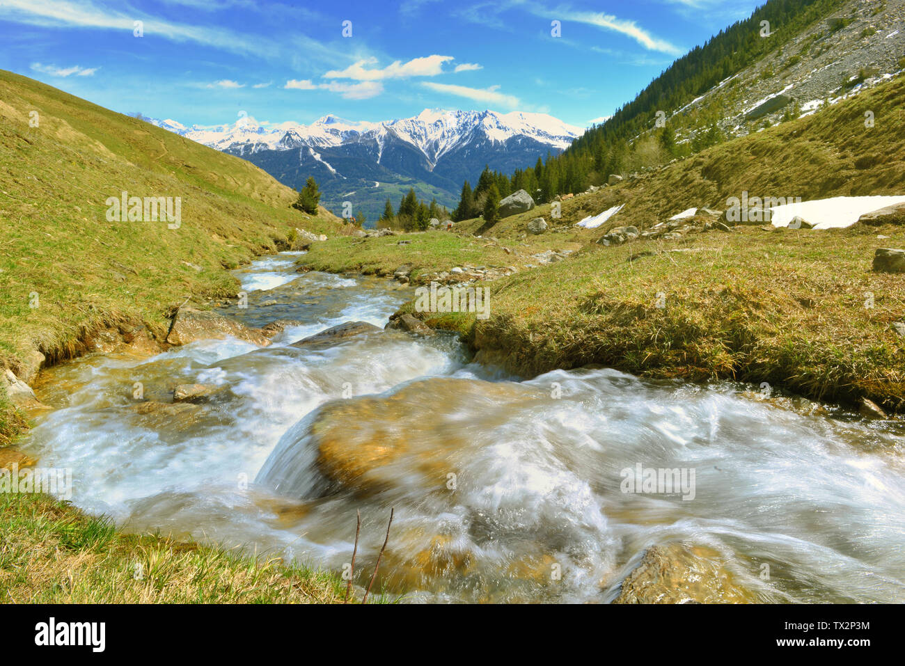 water of an alpine stream flowing in mountain and snowy peaks ...