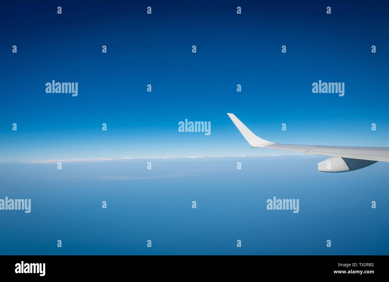 Wing of plane over white clouds. Airplane flying on blue sky. Scenic ...