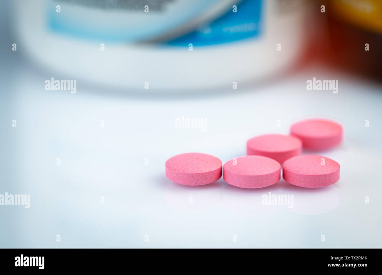 Round pink tablets pill on blurred drug bottle. Vitamins and minerals ...