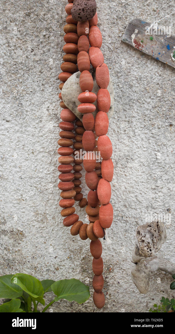Beads of polished stones hanging on the wall. Beads of pumice pebbles ...