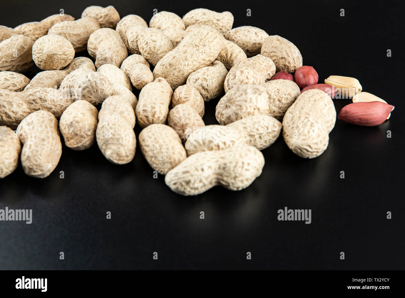 Peanuts in shells on a black background Stock Photo - Alamy