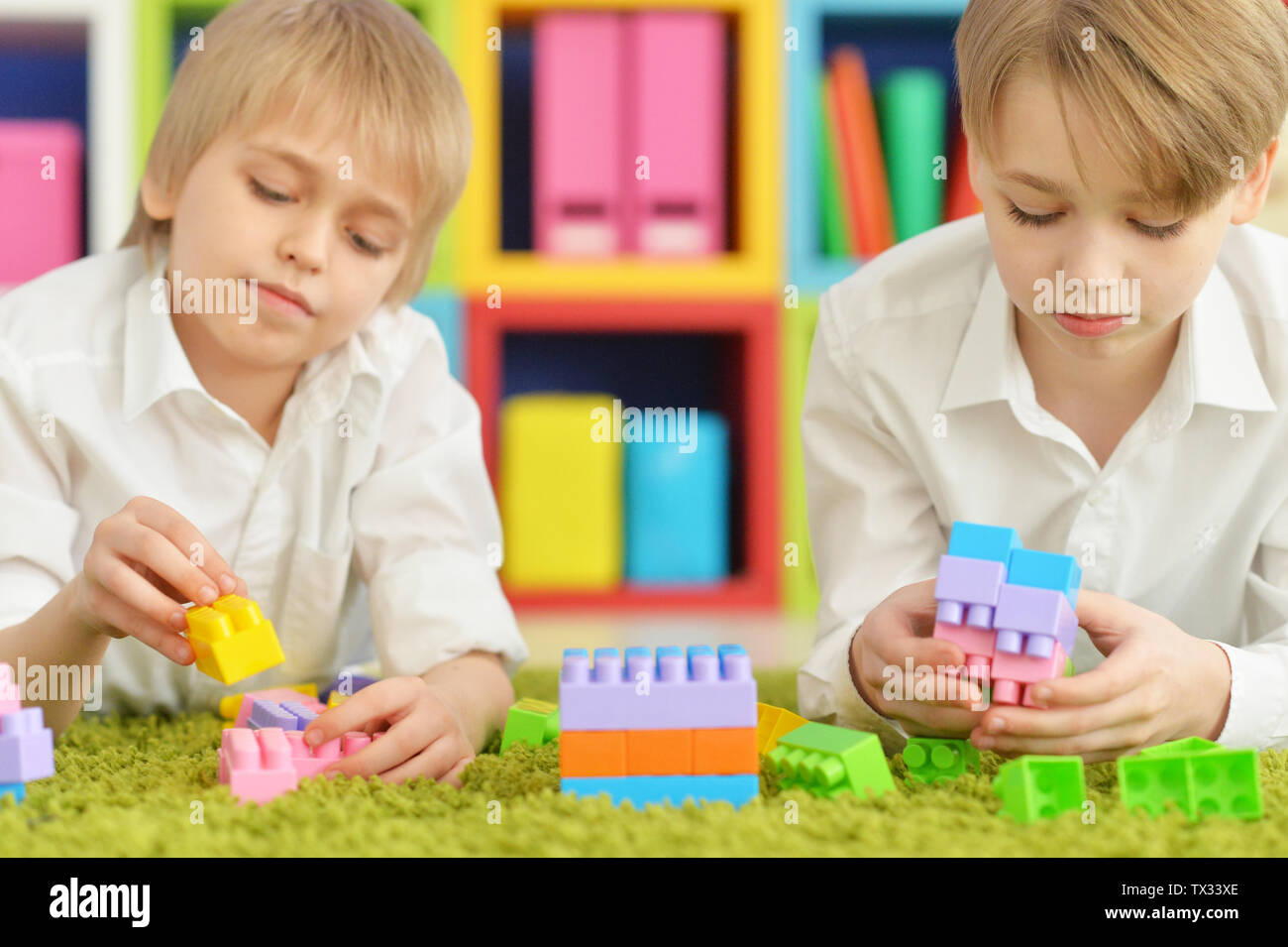 Two boys playing with colorful plastic blocks on floor Stock Photo - Alamy