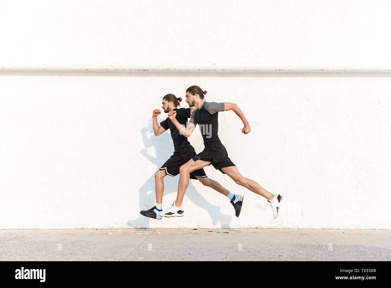 Full length of two healthy fit twin brothers exercising outdoors ...