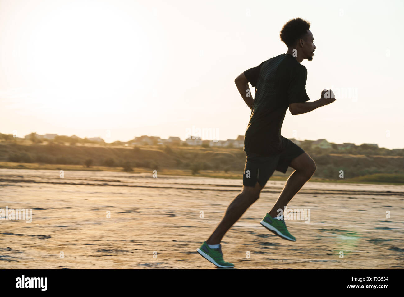Picture of a handsome young african strong sports man running outdoors ...
