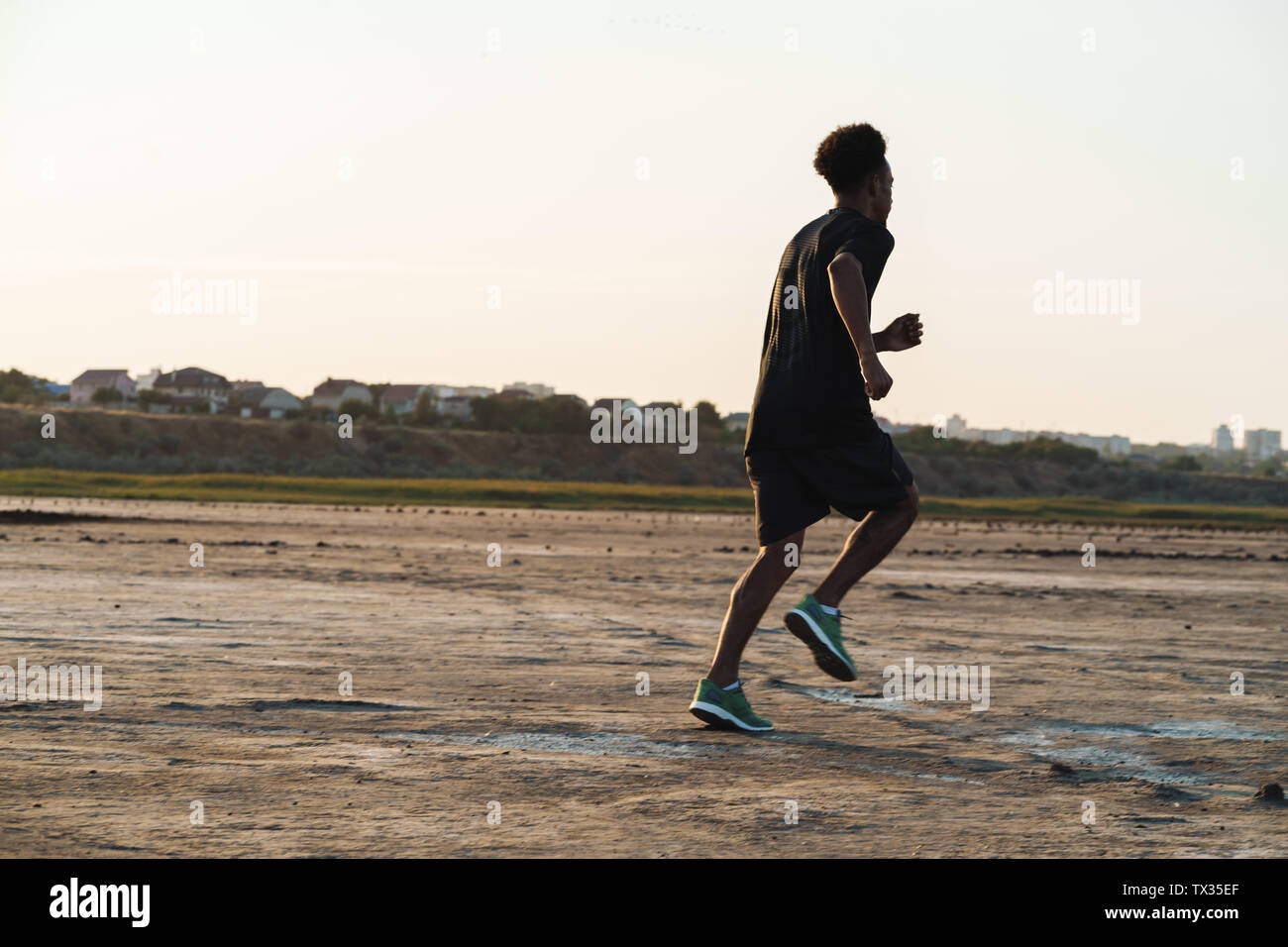 Picture of a handsome young african strong sports man running outdoors ...