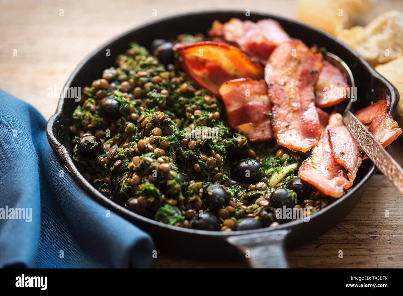 Brown lentils with spinach, black olives and fried bacon Stock Photo ...