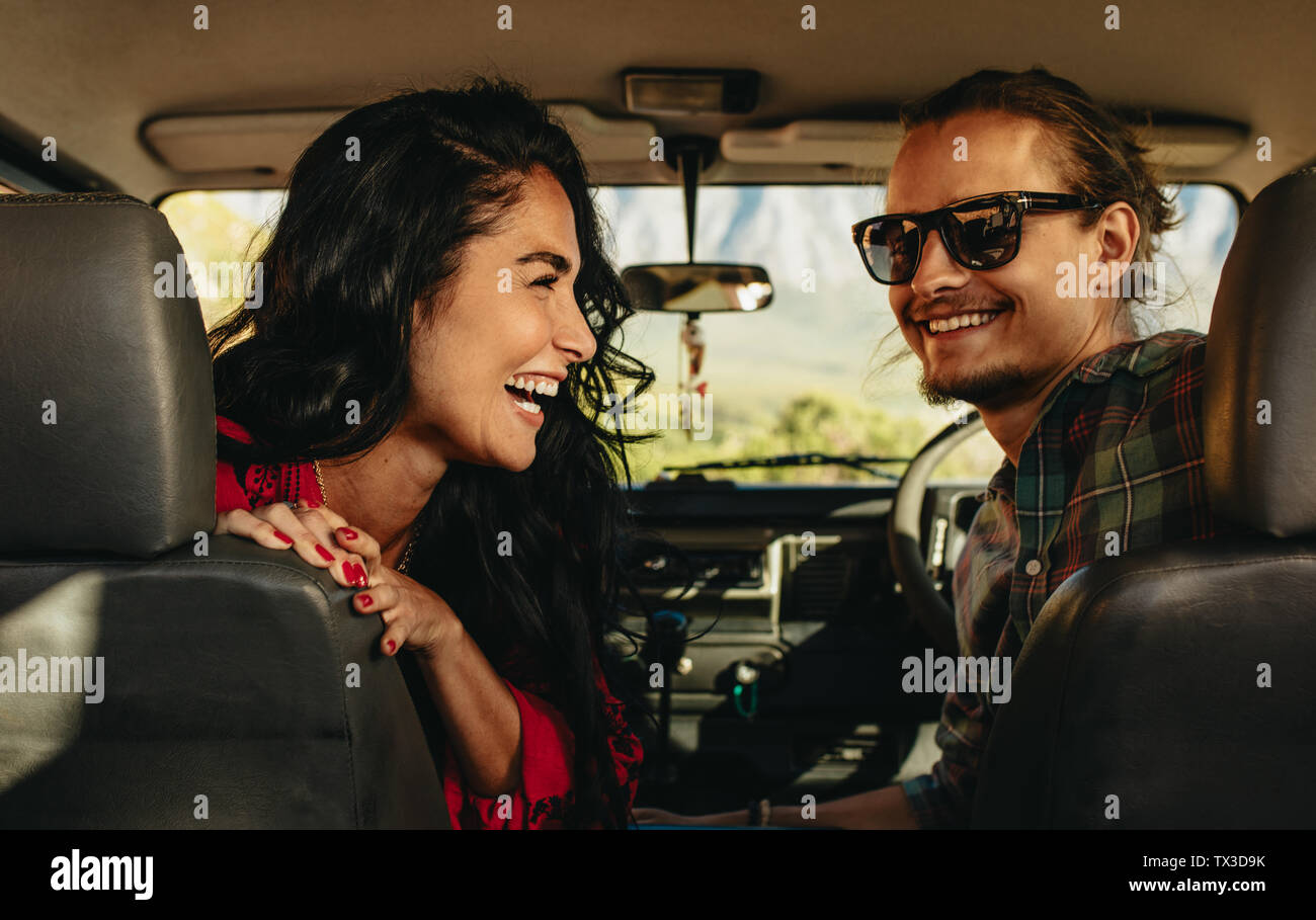 Rear view of a young couple on road trip. Smiling man and woman looking ...