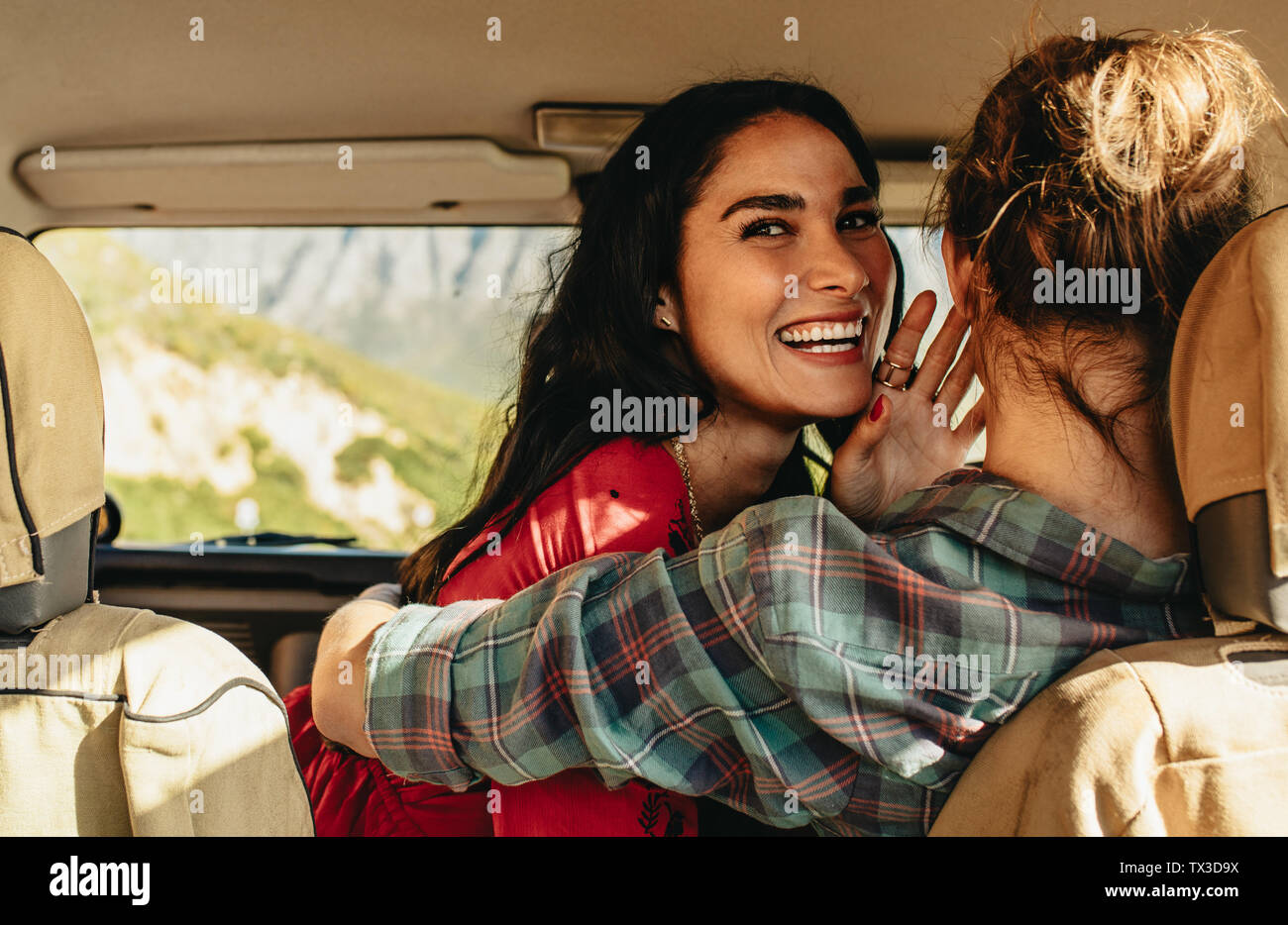 Smiling young woman embracing her boyfriend driving a car. Loving ...