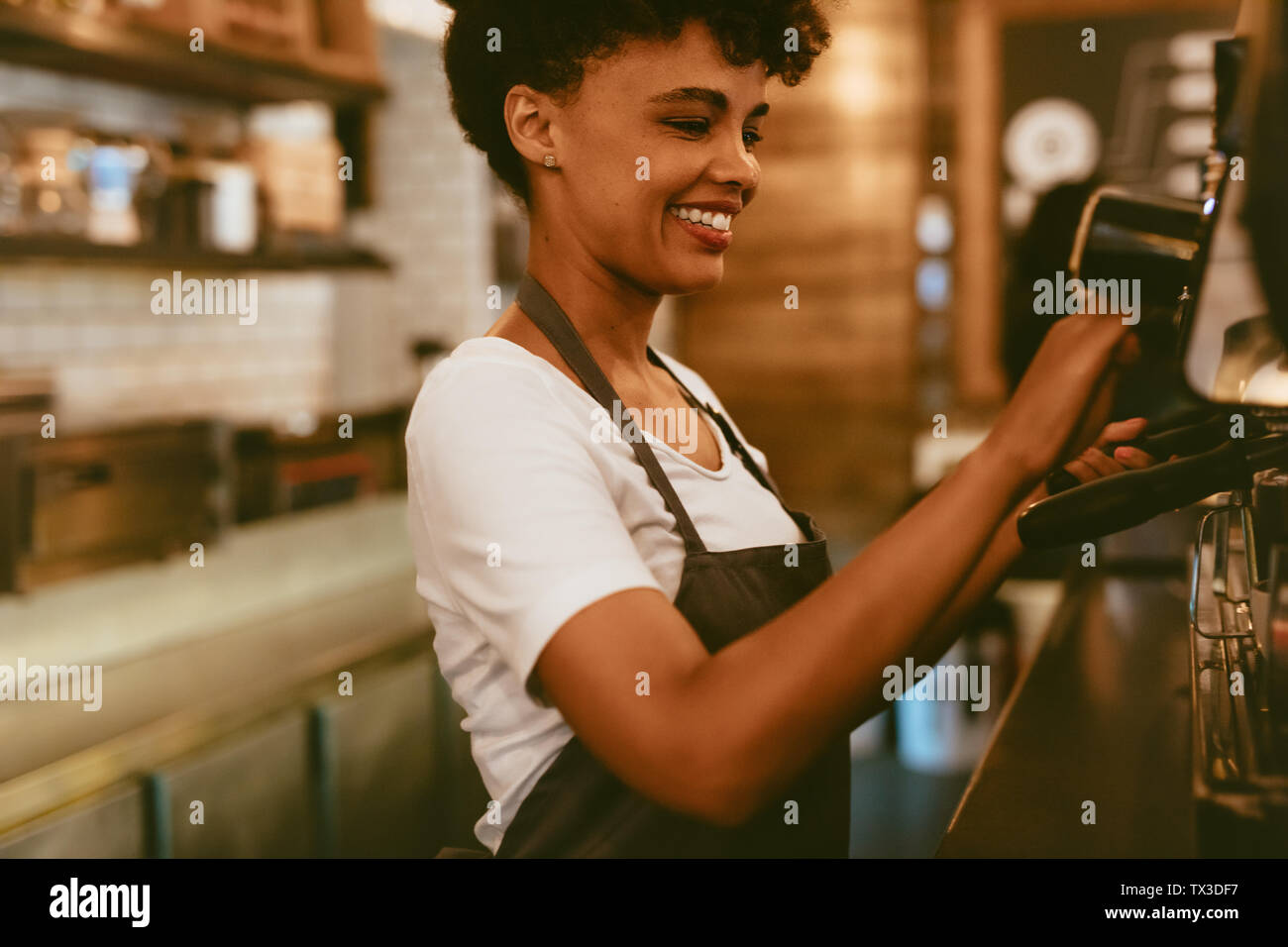 African female barista using a coffee maker to make a nice cup of ...