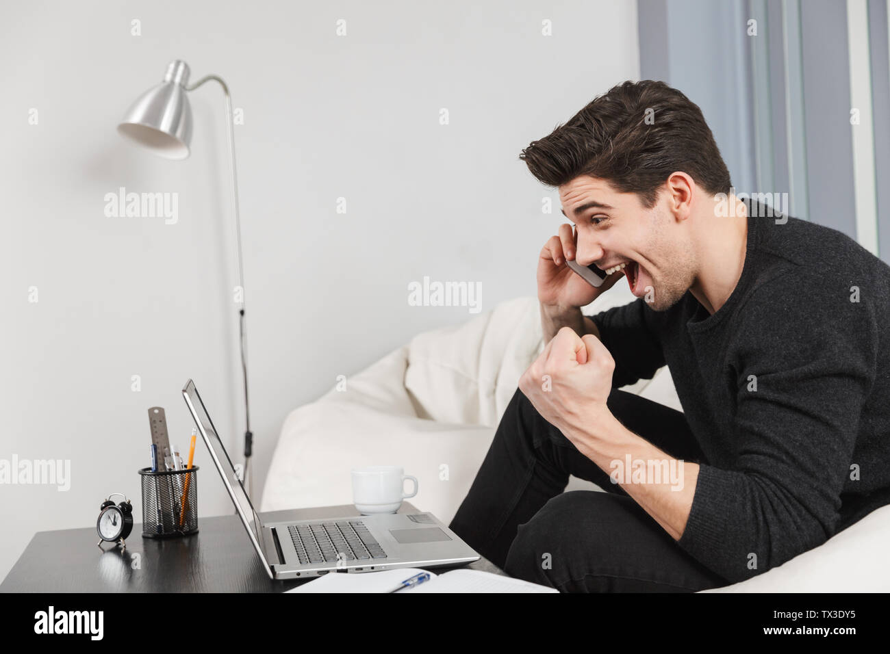 Image of a happy handsome young man at home indoors using laptop ...