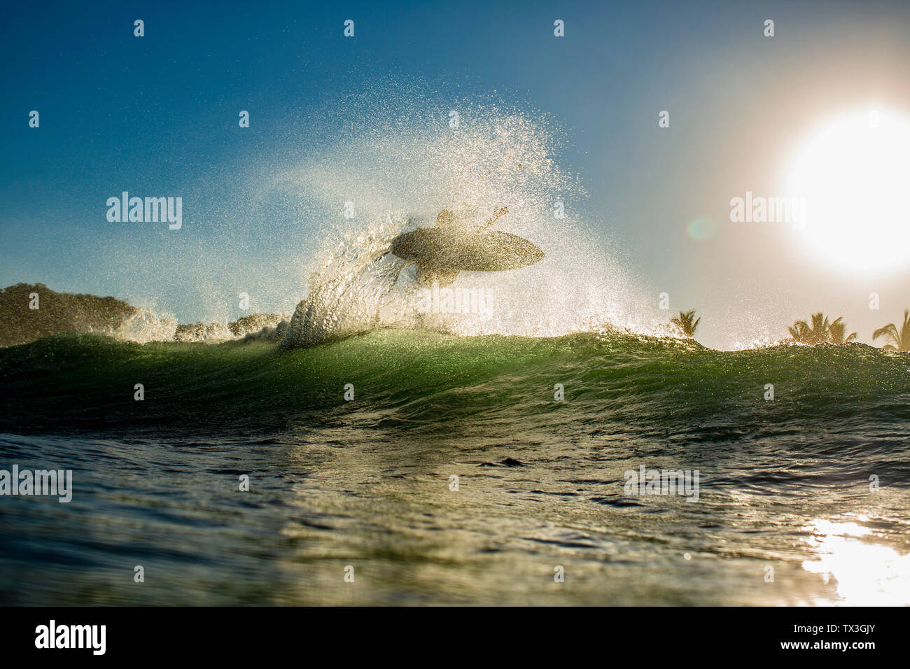 Surfer catching air behind ocean wave at sunrise, Sayulita, Nayarit ...