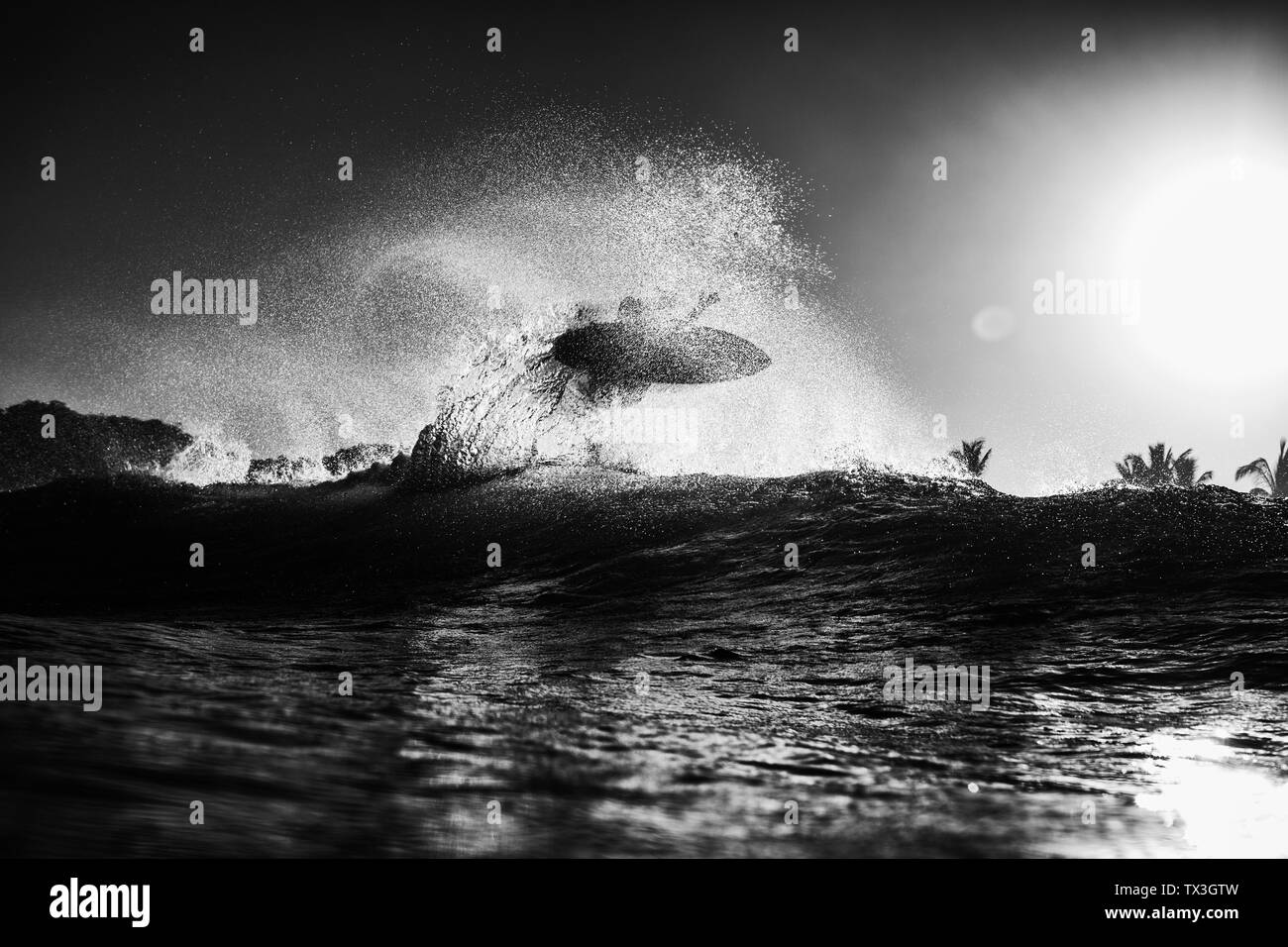 Surfer catching air behind ocean wave at sunrise, Sayulita, Nayarit ...