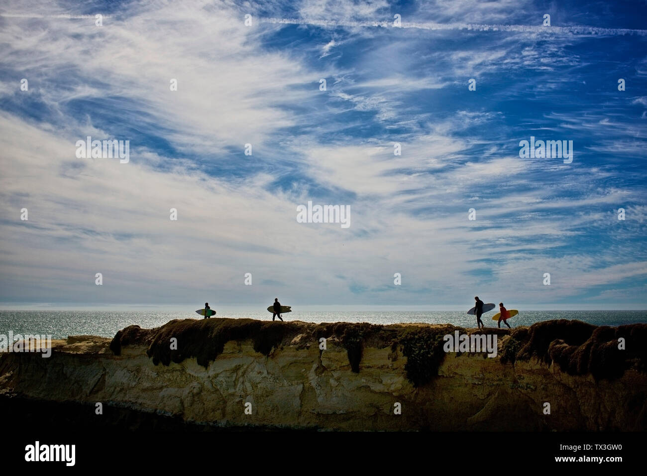 Surfers carrying surfboards on ocean rocks, Santa Cruz, California, USA ...