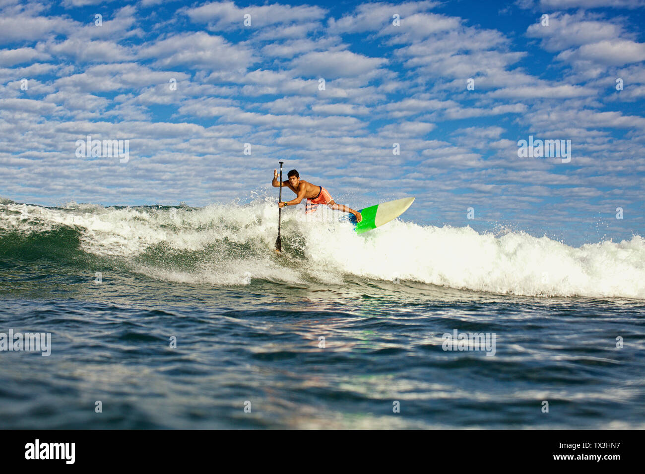 Young man paddleboarding ocean wave Stock Photo - Alamy