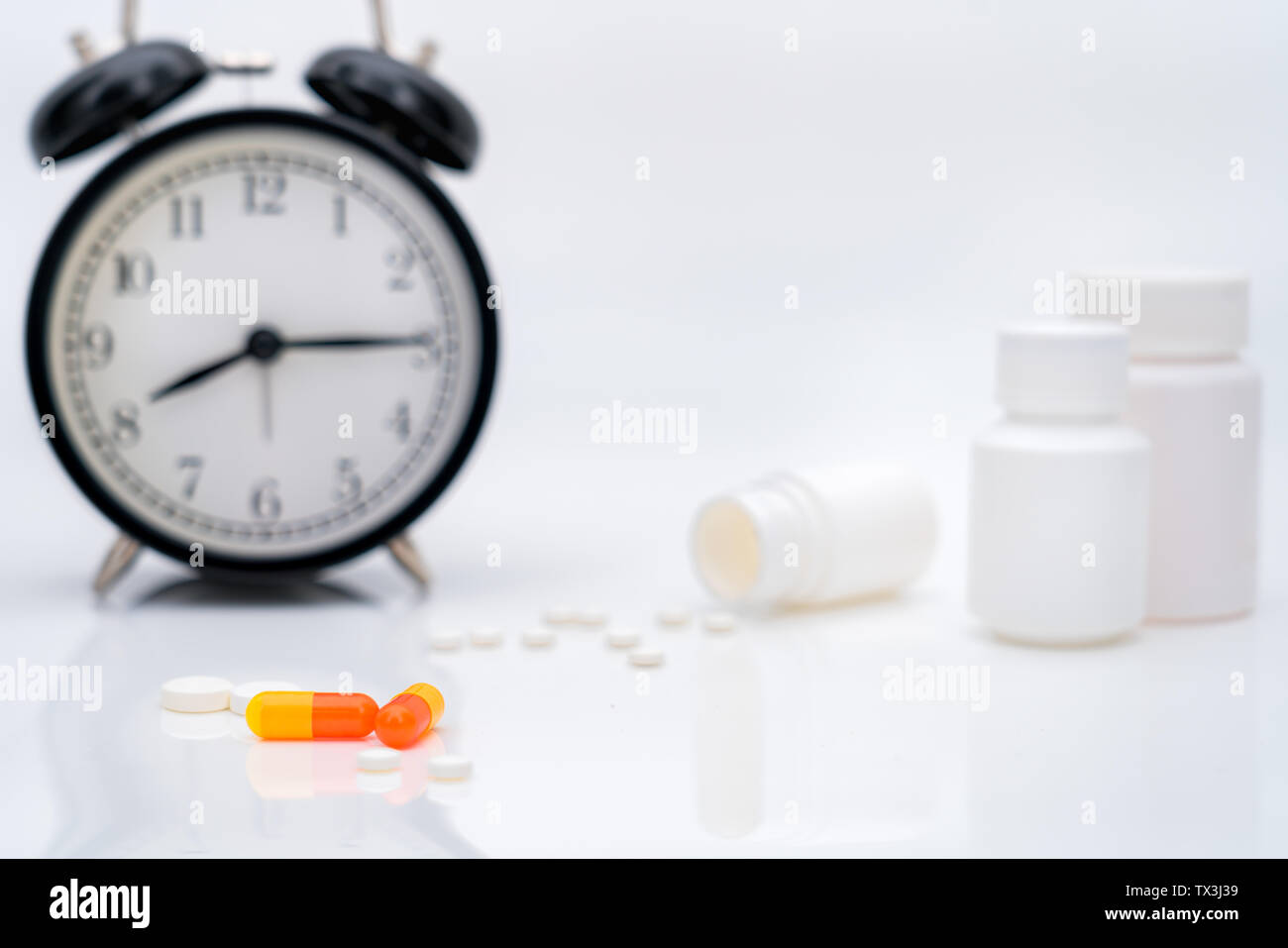 Tablets, capsules and alarm clocks on white background Stock Photo - Alamy