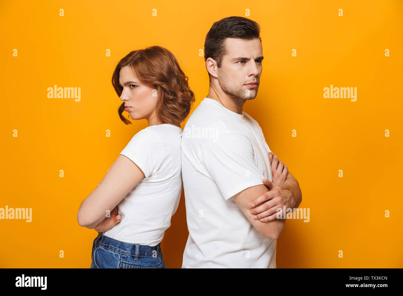 Angry beautiful couple wearing white t-shirts standing isolated over ...
