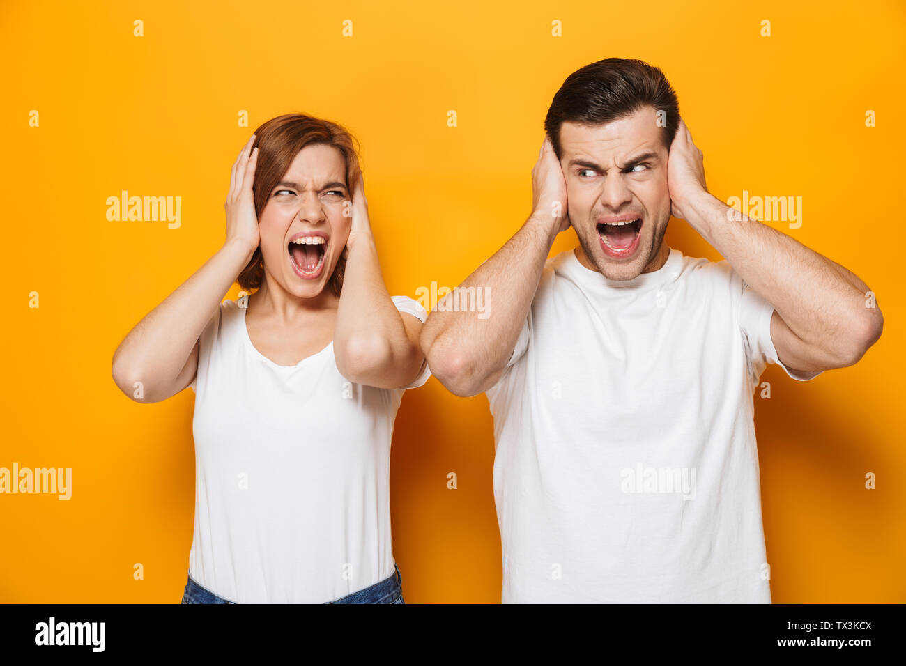 Angry beautiful couple wearing white t-shirts standing isolated over ...