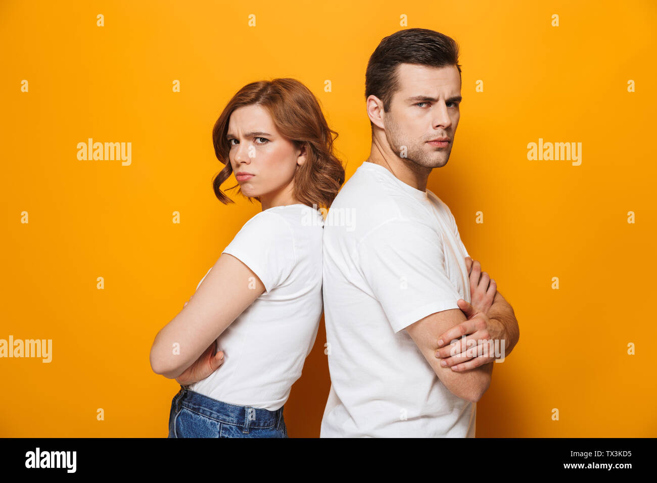 Angry beautiful couple wearing white t-shirts standing isolated over ...