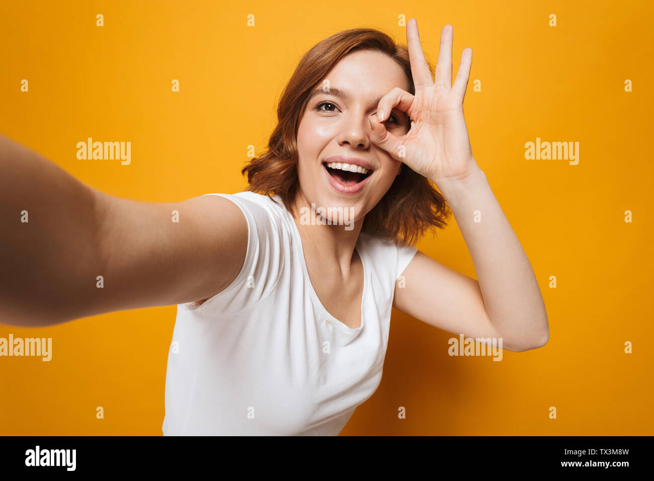 Portrait of a happy lovely girl standing isolated over yellow ...