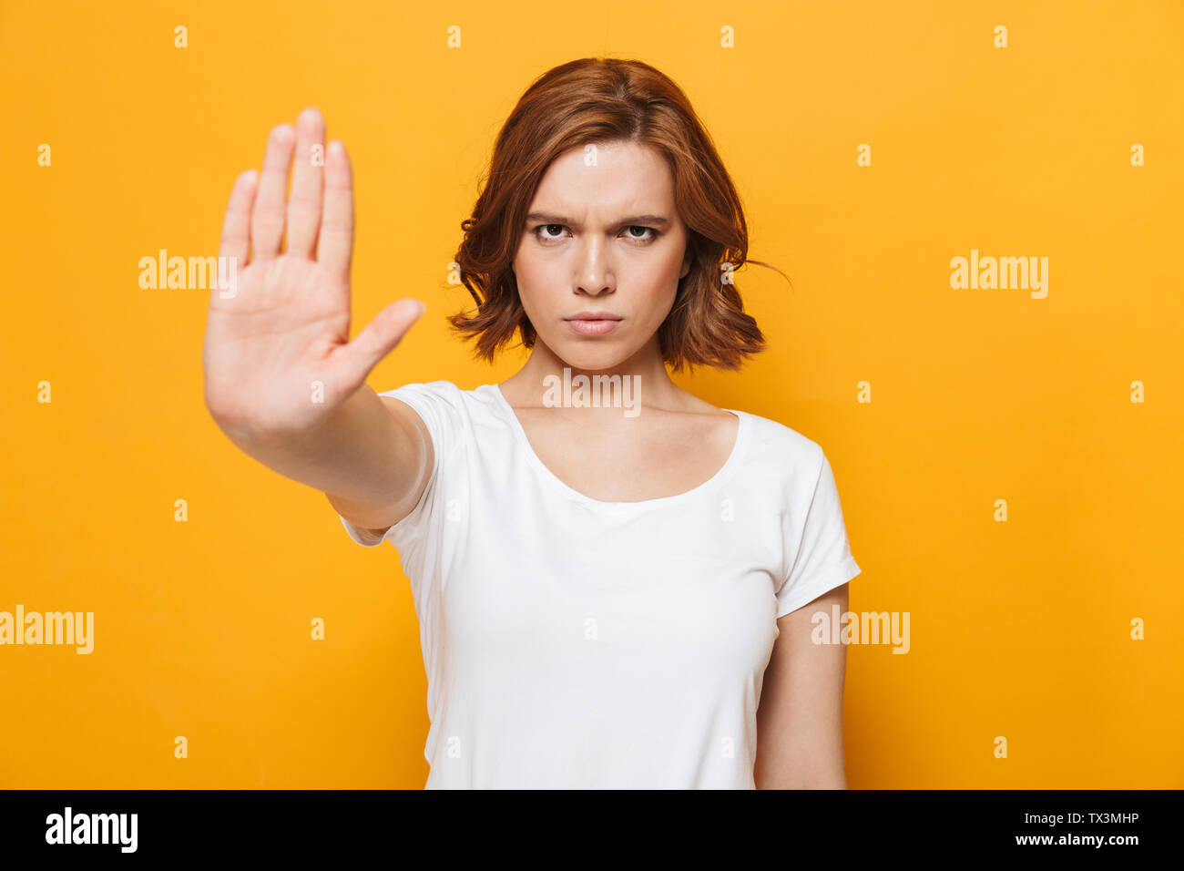 Portrait of an angry lovely girl standing isolated over yellow ...