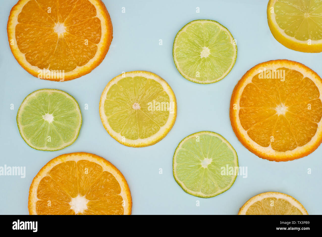 Sliced citrus on blue background. Orange, lemon and lime Stock Photo ...