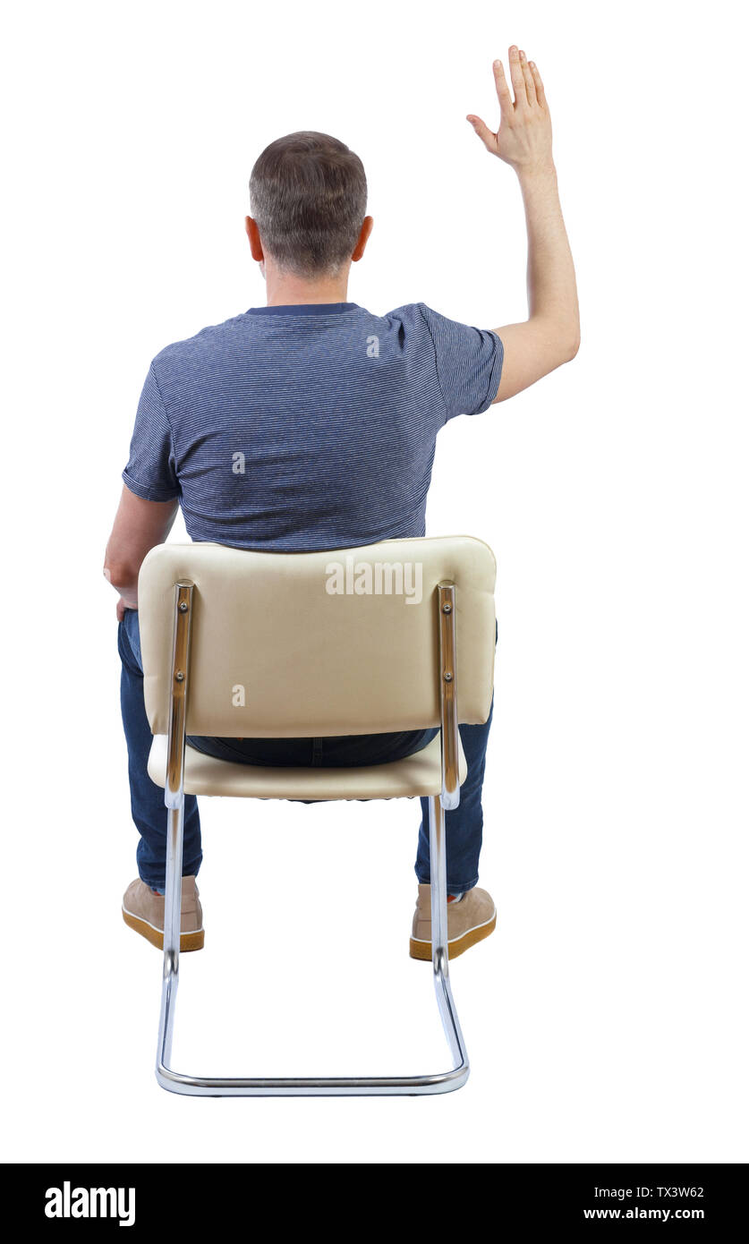 Back view of a man sitting on a chair and raising a hand to ask a ...