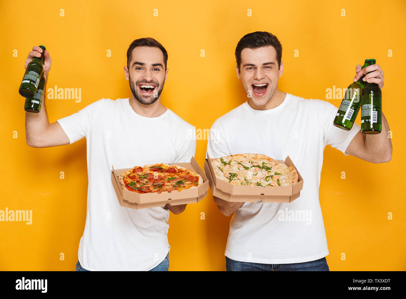 Image of two joyous men bachelors 30s in white t-shirts holding pizza ...