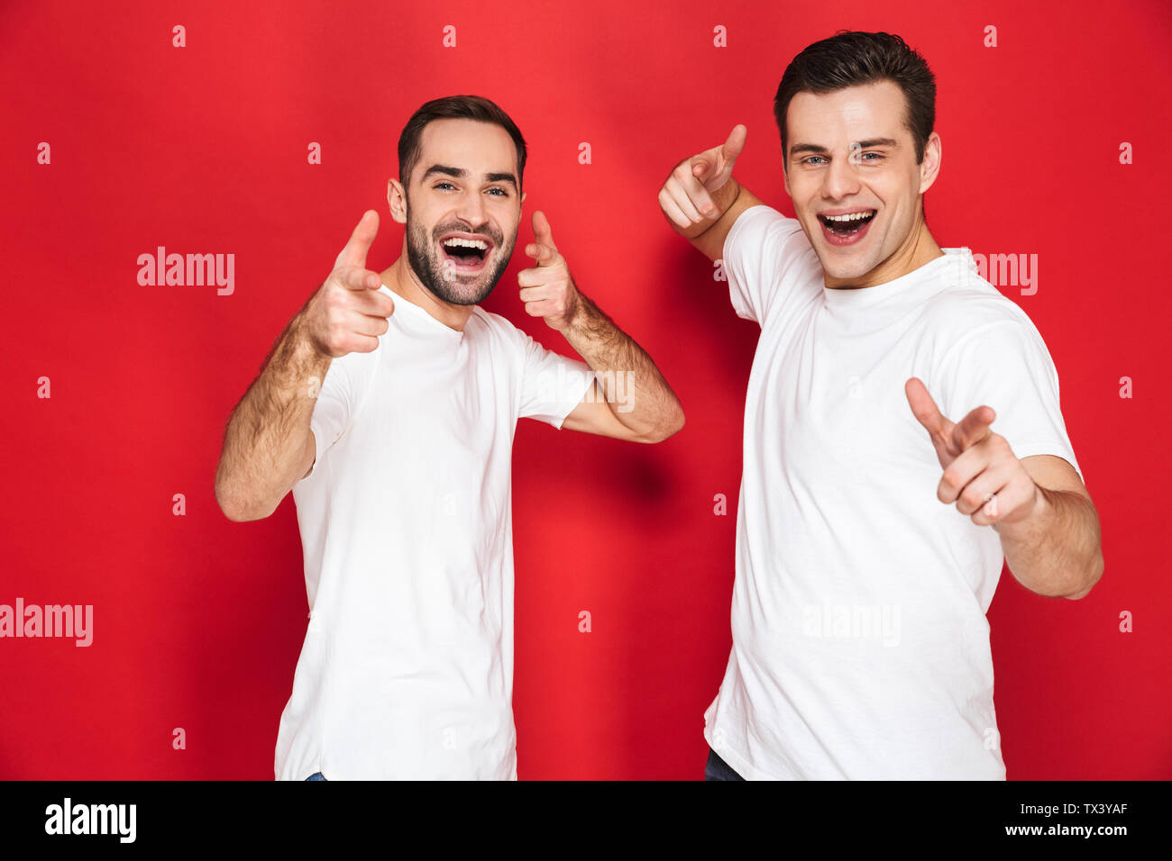 Image of two beautiful men friends 30s in white t-shirts smiling and ...