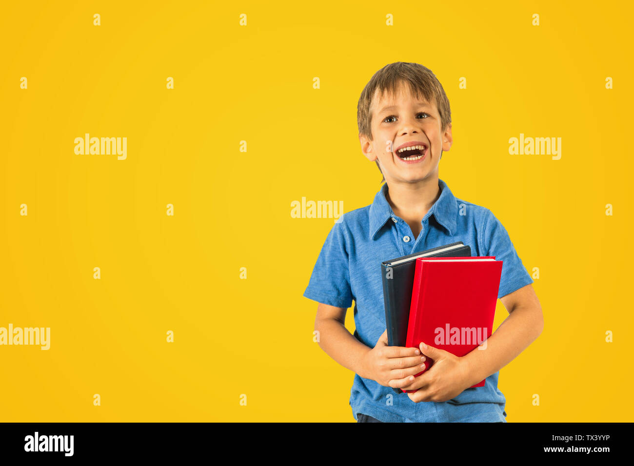 Happy pupil schoolboy with books on yellow background Stock Photo - Alamy