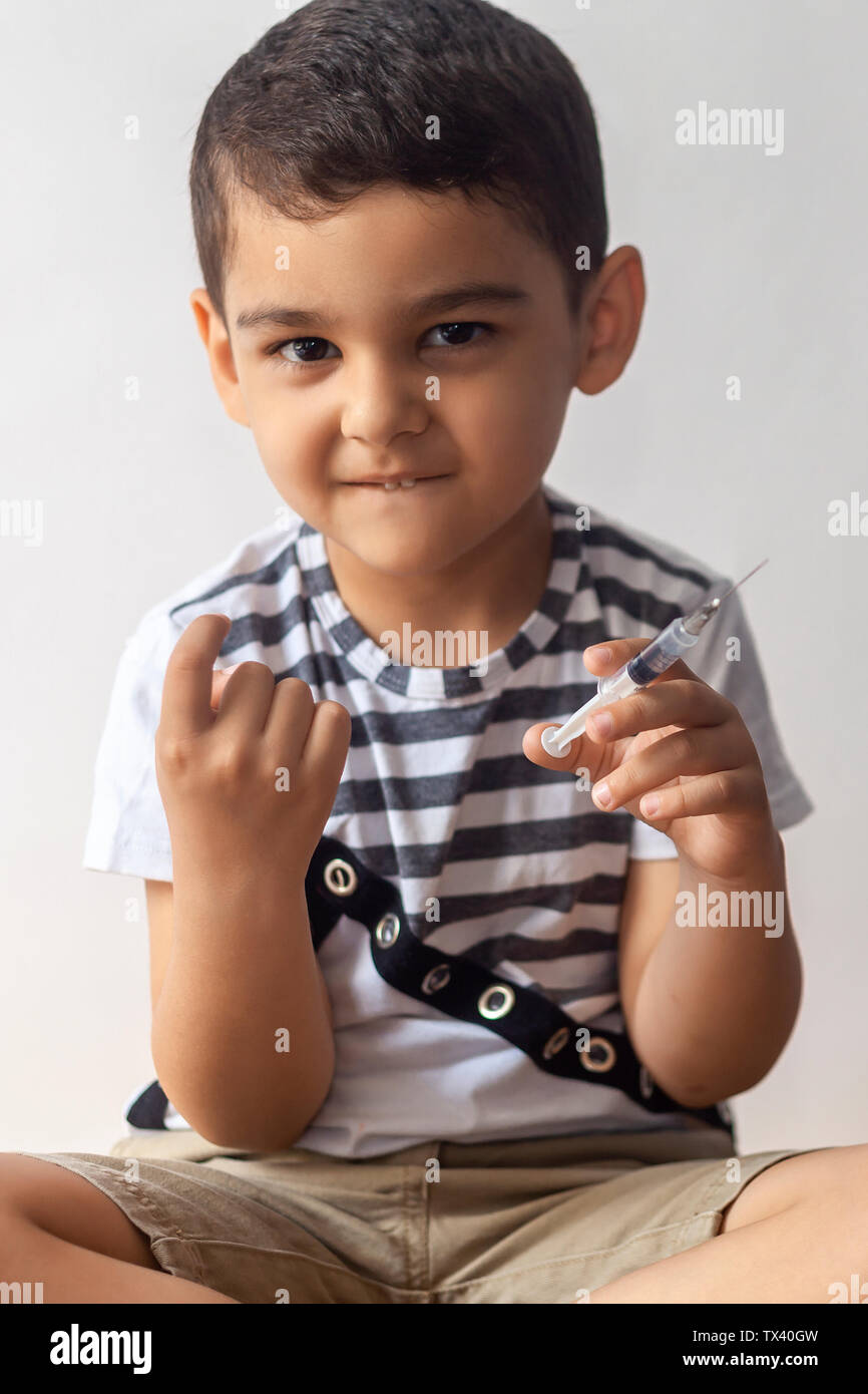 A little bad boy holding the syringe and calling someone with his ...