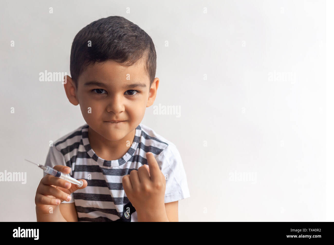 A little bad boy holding the syringe and calling someone with his ...