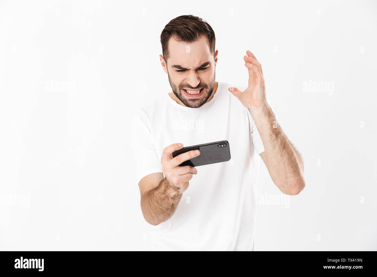 Handsome angry man wearing blank t-shirt standing isolated over white ...