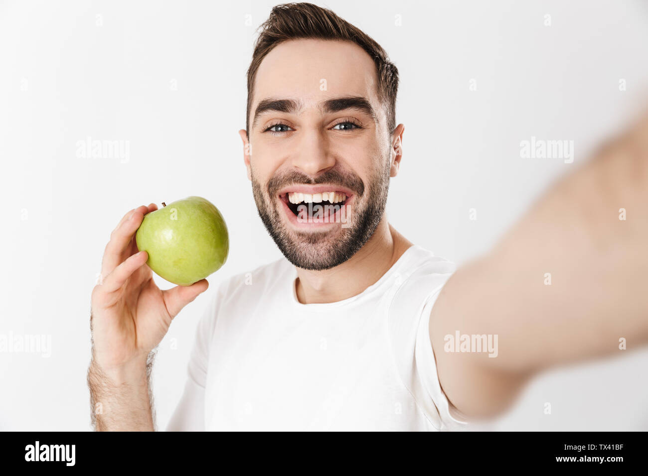 Handsome cheerful man wearing blank t-shirt standing isolated over ...