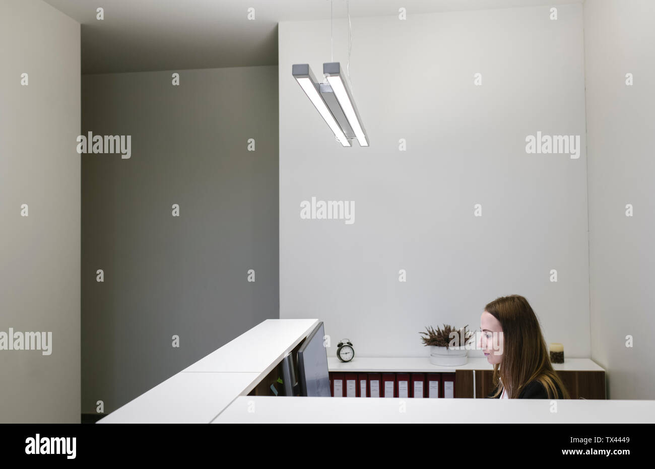 Young woman working at the reception desk in office Stock Photo - Alamy