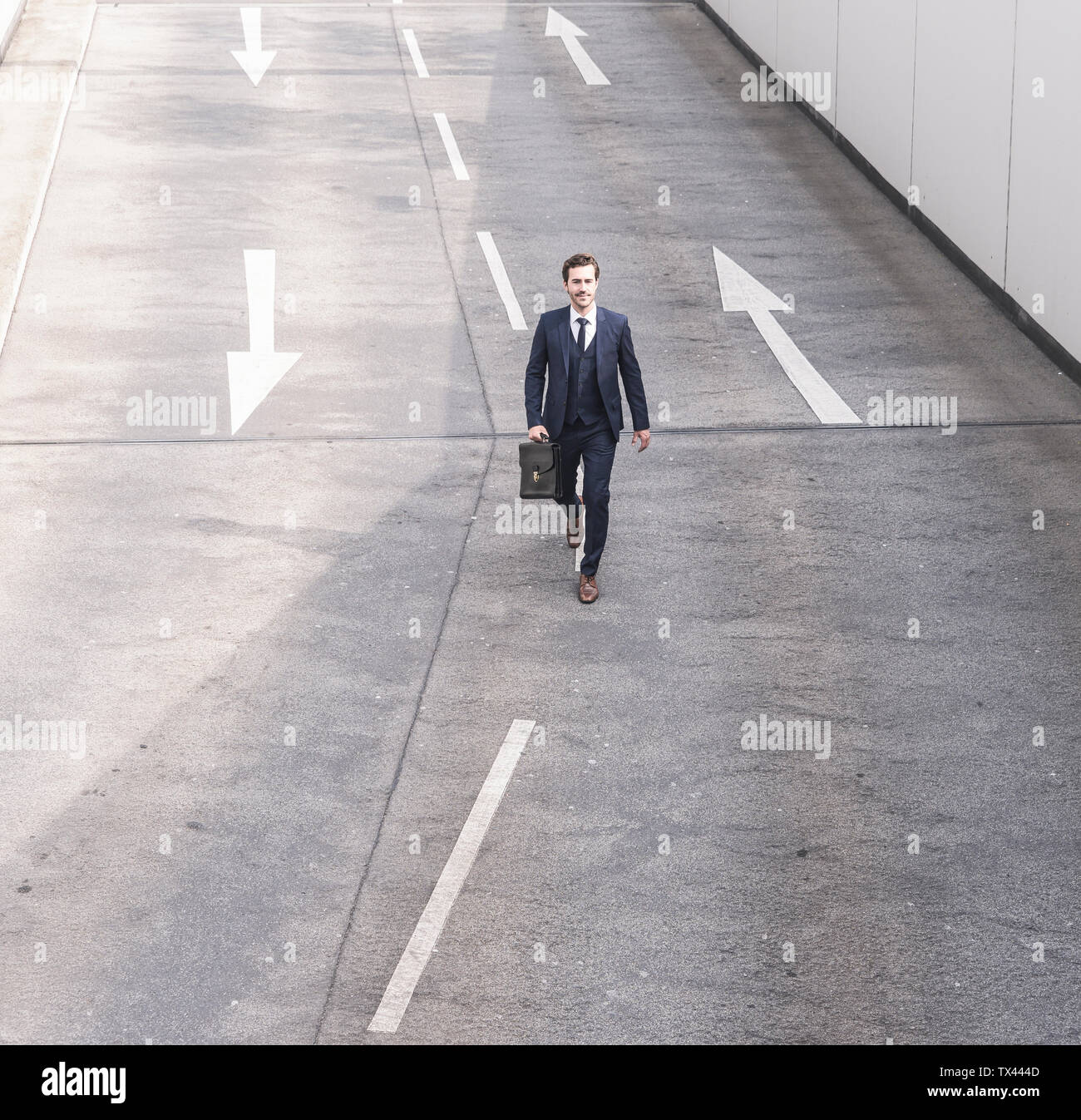 Businessman walking on road with arrow signs Stock Photo - Alamy