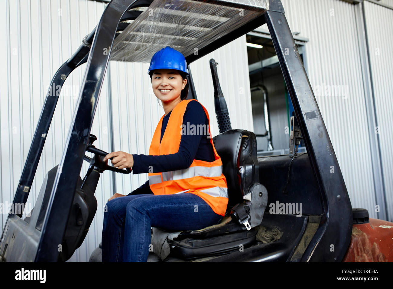 Portrait of confident female worker on forklift in factory Stock Photo ...