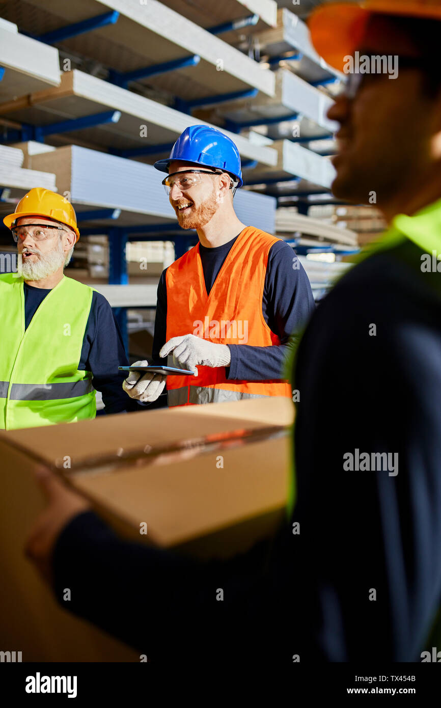 Happy workers talking in factory warehouse Stock Photo - Alamy