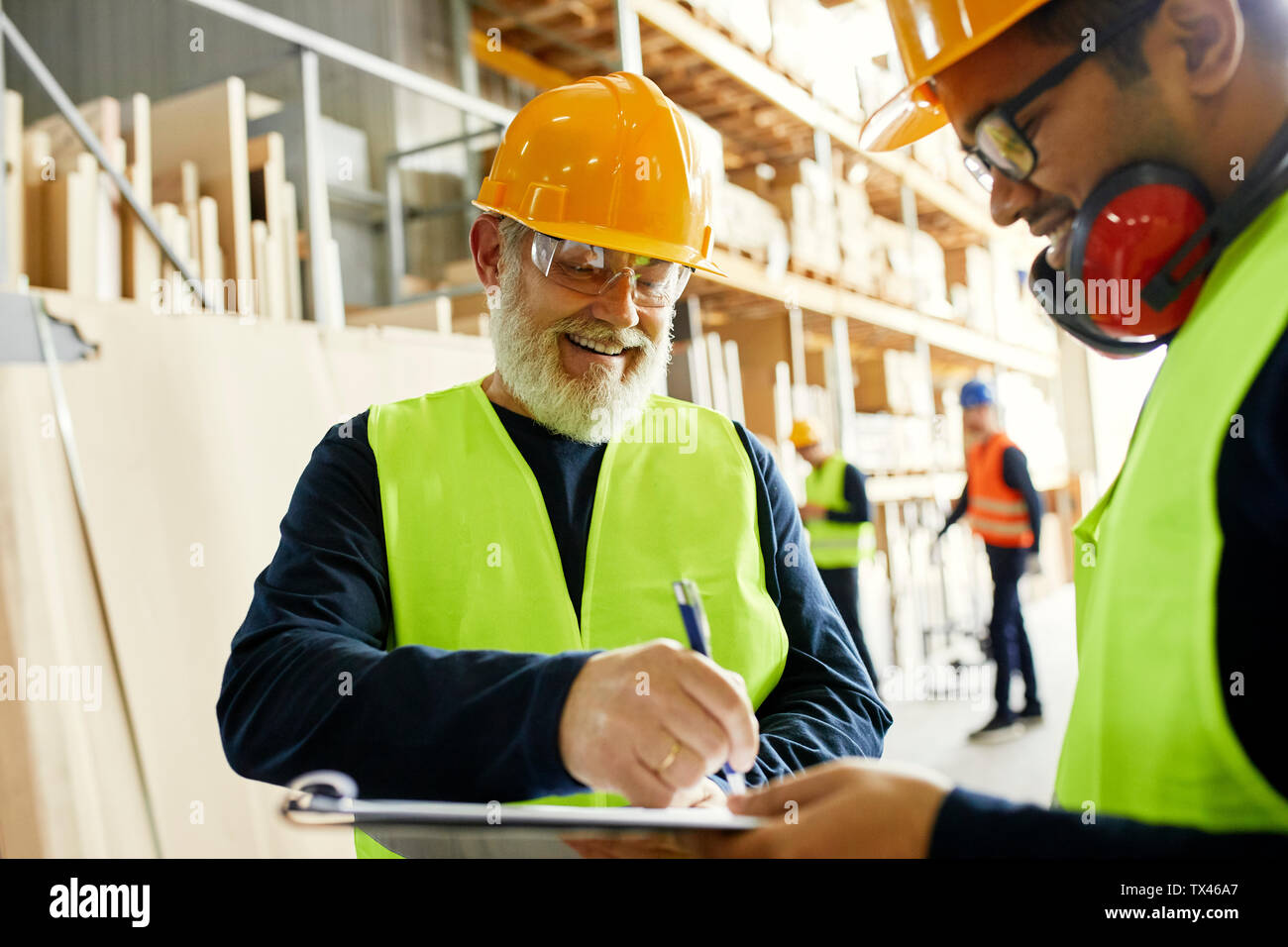 Two smiling men signing document in factory warehouse Stock Photo - Alamy