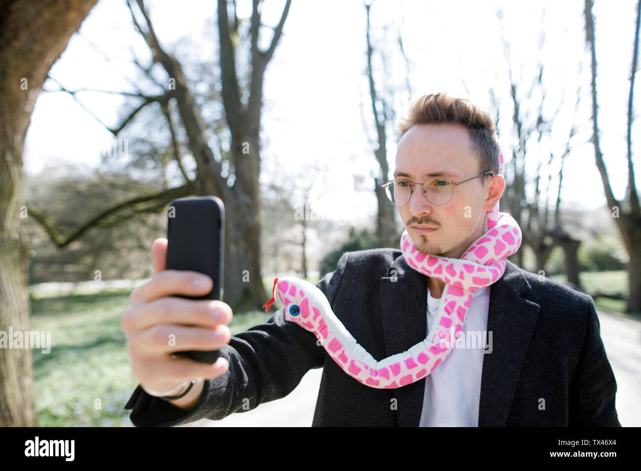 Young man wearing toy snake around his neck taking a selfie Stock Photo ...