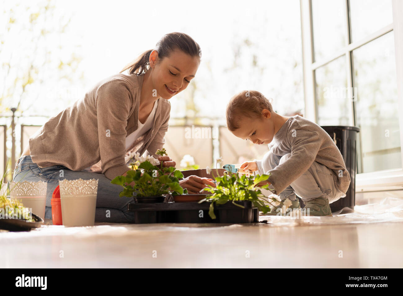 Mother and daughter planting flowers together on balcony Stock Photo ...