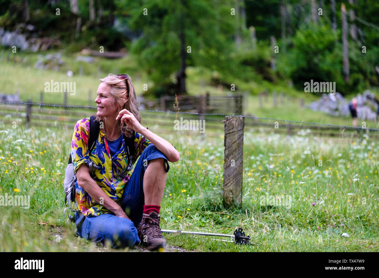 Female hiker sitting on meadow Stock Photo - Alamy