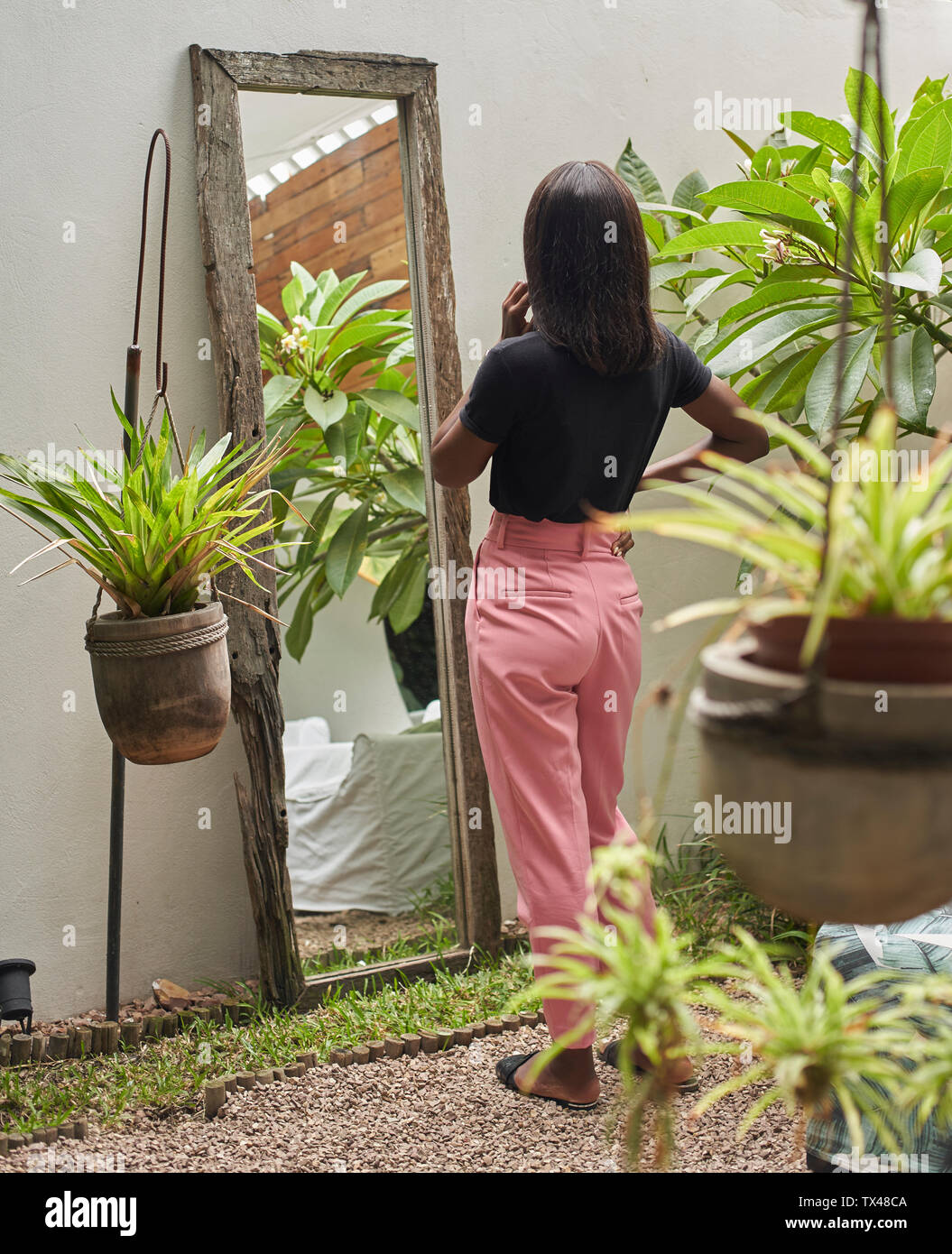 Back view of woman standing in a courtyard looking at mirror Stock ...