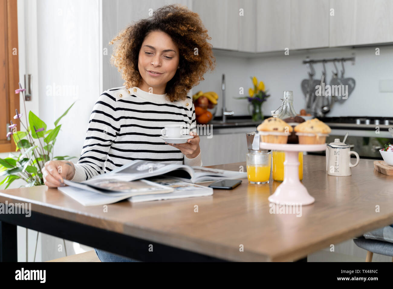 Woman sitting in kitchen, reading magazines and drinking coffee Stock ...