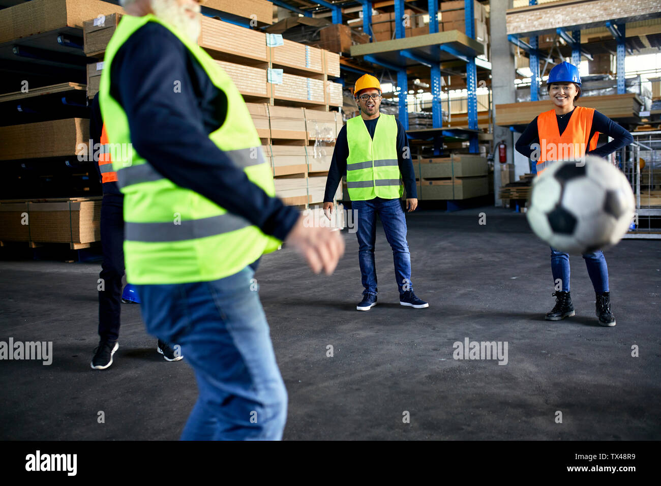 Workers playing football in factory warehouse Stock Photo - Alamy