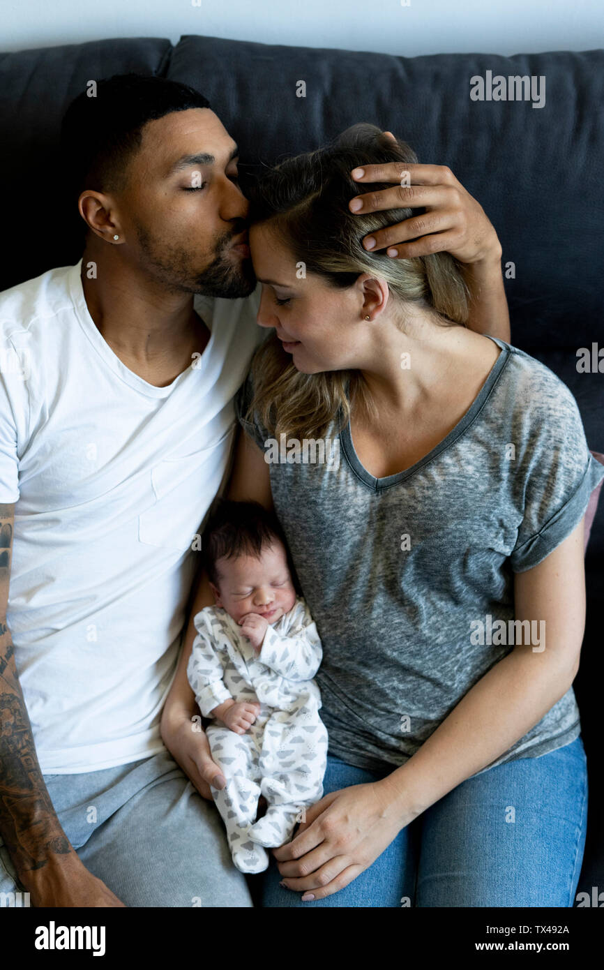 Parents cuddling with newborn baby on couch Stock Photo - Alamy