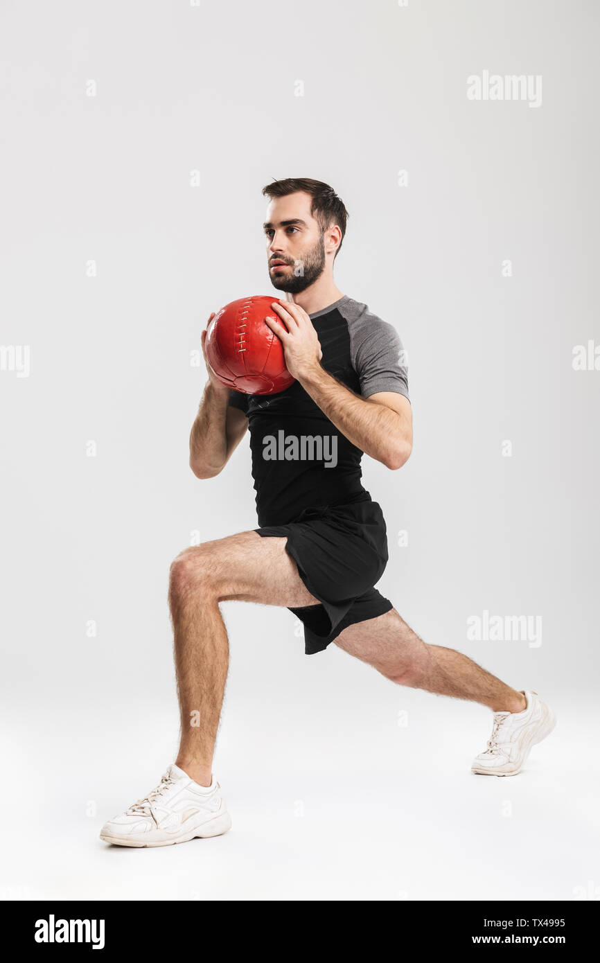 Confident motivated sportsman doing exercises with heavy ball isolated ...