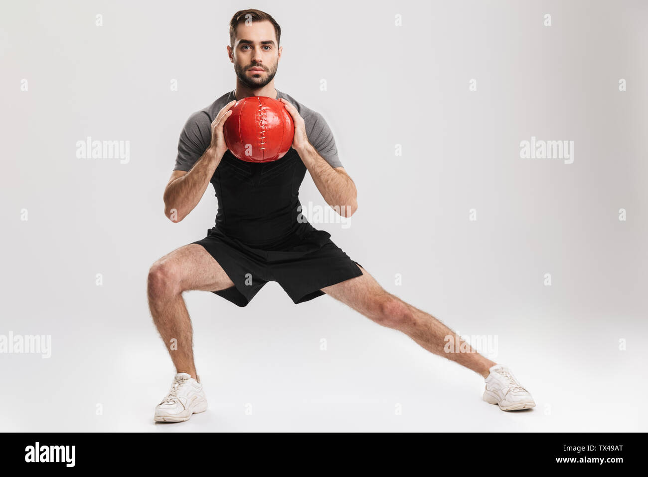 Confident motivated sportsman doing exercises with heavy ball isolated ...