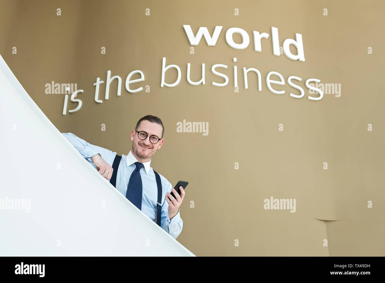 Portrait of confident businessman with cell phone on stairs in modern office Stock Photo - Alamy