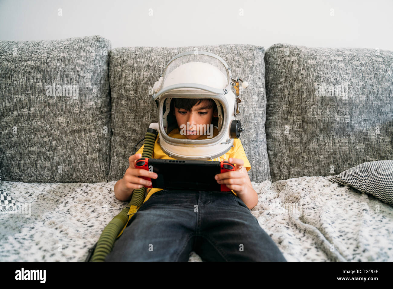 Boy playing video game on a games console, wearing space hat Stock ...